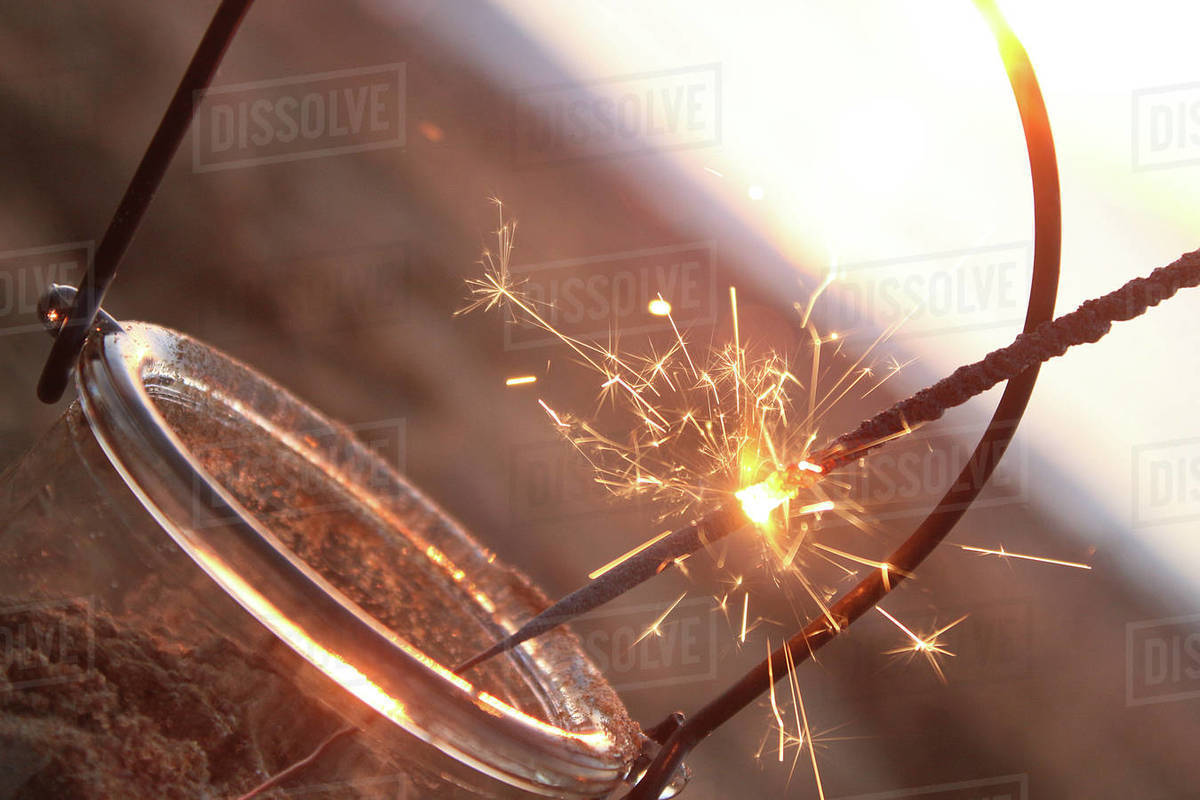 Lit sparkler in a jar on the beach - Royalty-free Stock Photo | Dissolve