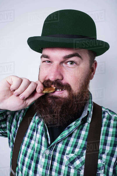 Portrait of a man biting a gold coin - Stock Photo - Dissolve