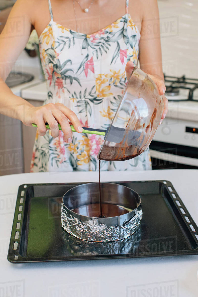Woman pouring cake batter into a cake tin - Stock Photo - Dissolve