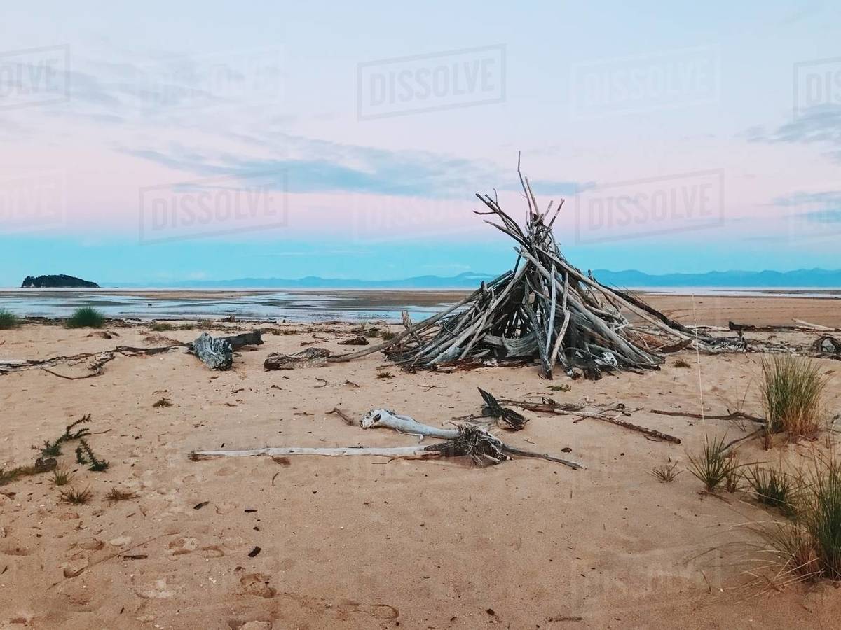 Log den on beach at sunset, Abel Tasman National Park, South Island ...