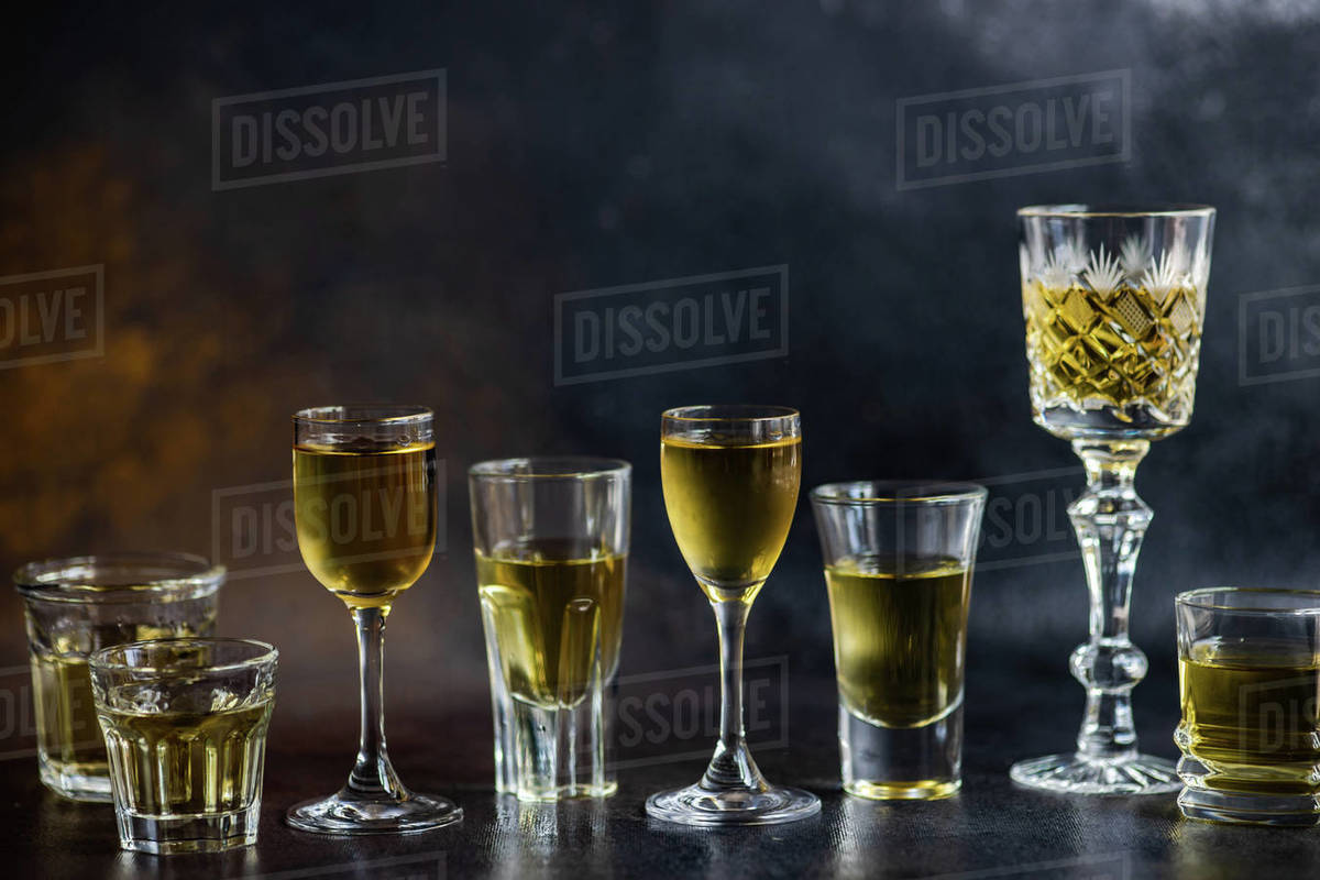 Row of assorted shot glasses, wine glasses and tumblers filled with ...