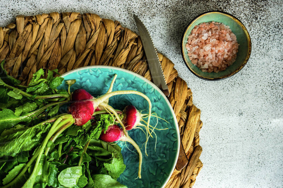 Overhead view of a plate of fresh radishes with pink Himalayan salt ...