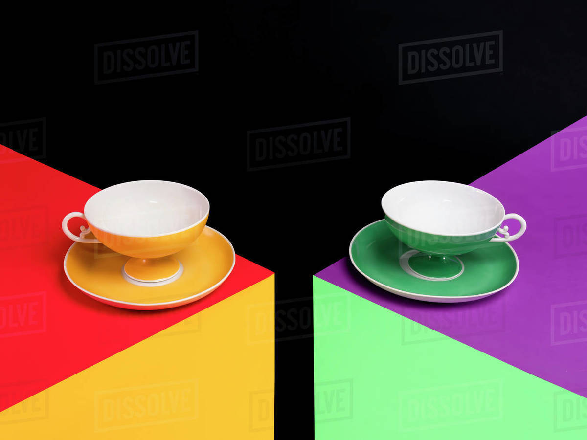 Two colourful empty teacups levitating off saucers on two multi ...