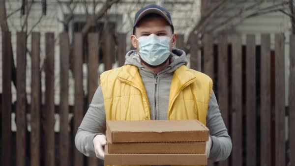 Delivery man holding cardboard boxes in medical rubber gloves and mask ...