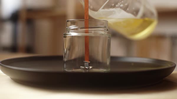Close-up front view of unrecognizable female artisan pouring melted wax ...
