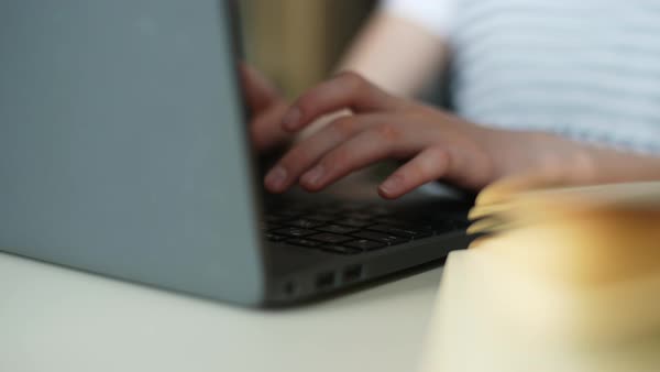 Close-up tracking shot of unrecognizable child school girl typing on ...