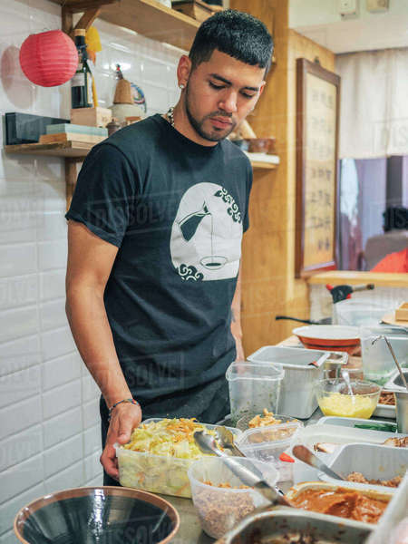 Handsome ethnic man standing in kitchen and choosing ingredients for ...