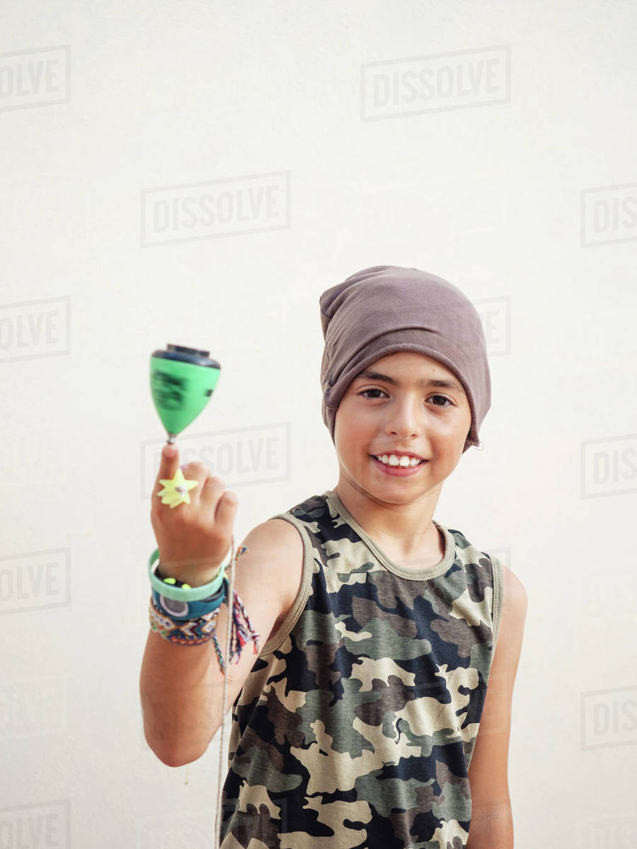 Smart stylish boy in hat easily spinning green top while looking at ...