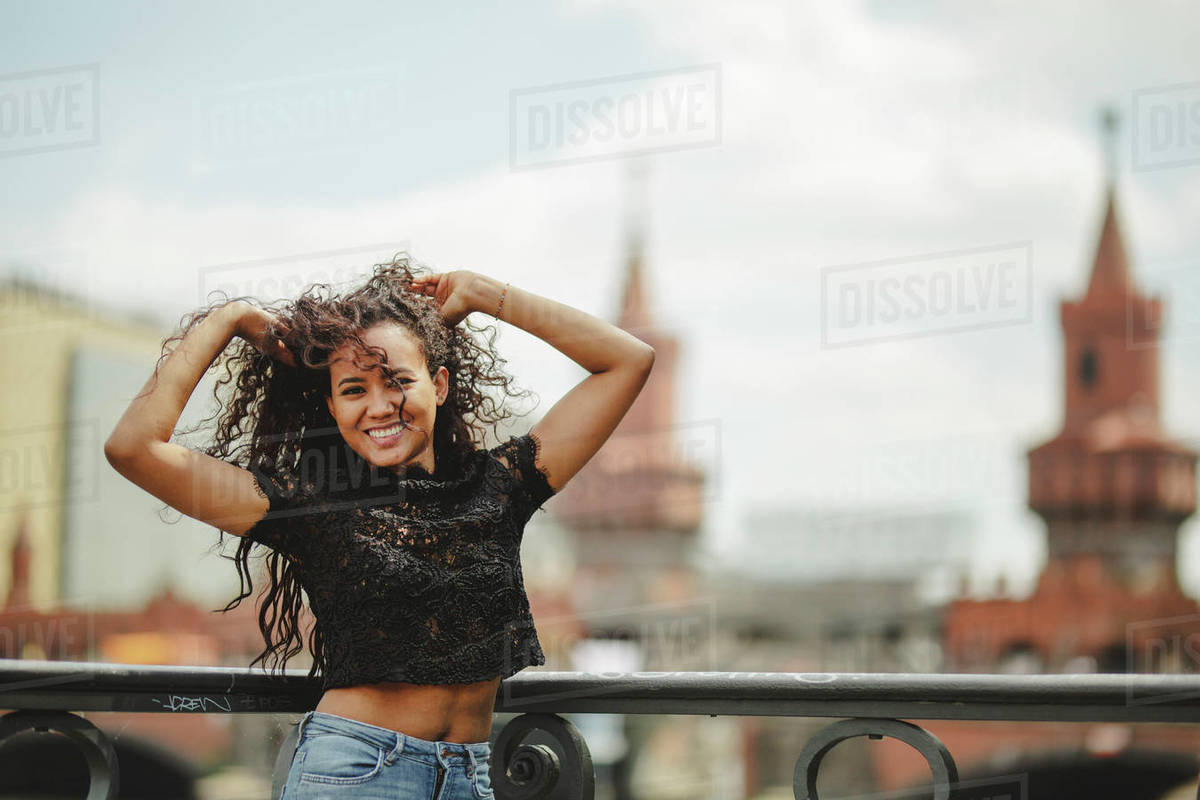 Beautiful ethnic female model leaning on railing on summer day in ...