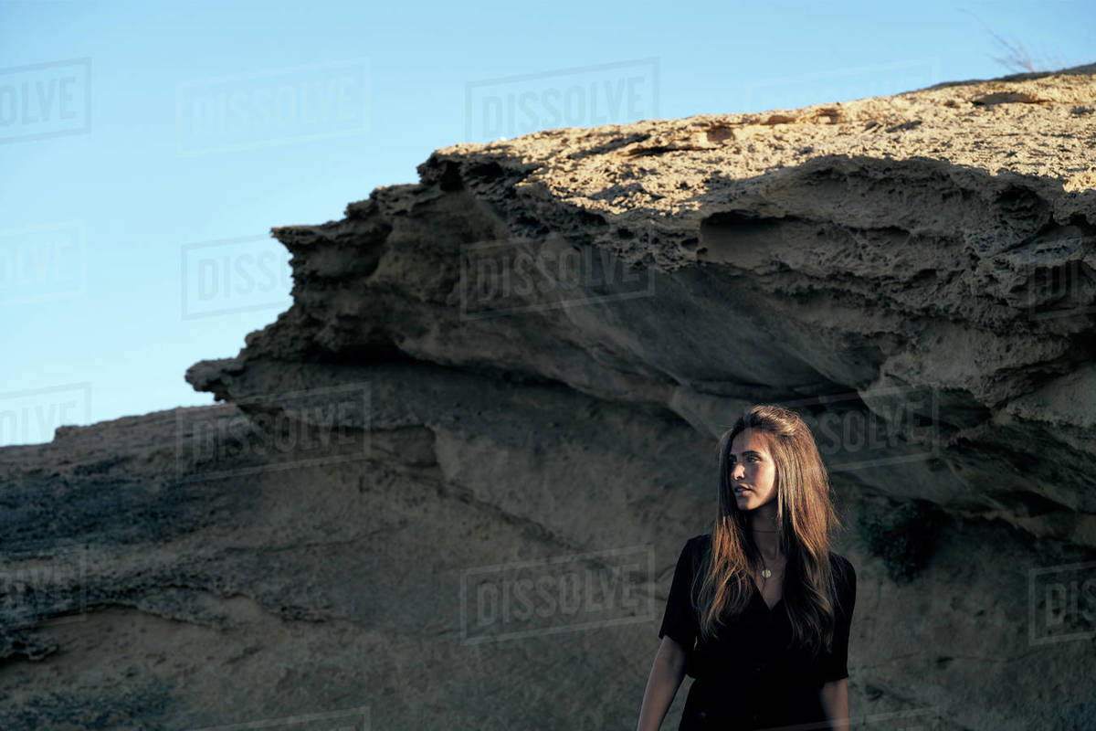 Young long haired stylish pensive female model looking down standing in ...