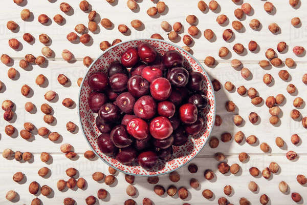 Top view of fresh sweet cherries in bowl with cherry seeds around on ...