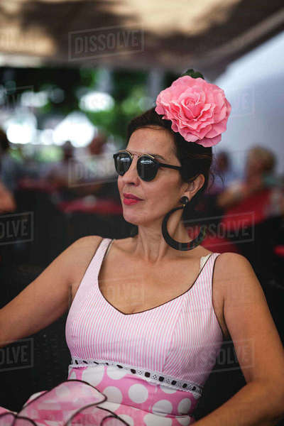 Eccentric woman in colorful pink costume sitting on summer street ...