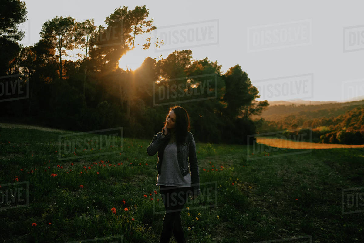 Side view of relaxed young female in black jacket enjoying nature and ...