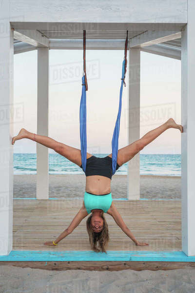 Relaxed woman performing aerial yoga hanging head down - Royalty-free ...
