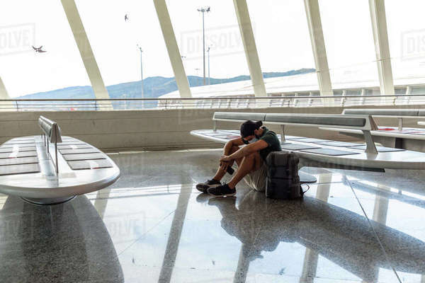 Side view of discouraged male tourist in protective mask sitting on ...