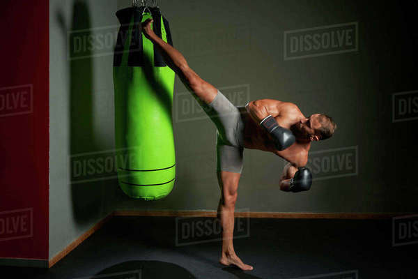 Full length of enduring shirtless male kickboxer in boxing gloves ...