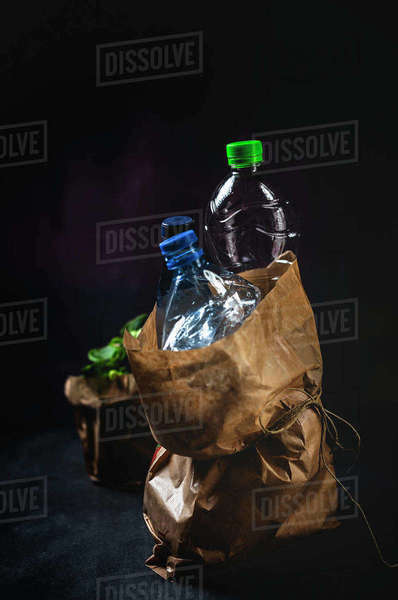Dirty paper sack with discarded plastic bottles placed on black ...