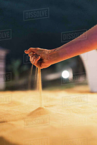 Crop hand spilling dry sand - Royalty-free Stock Photo | Dissolve