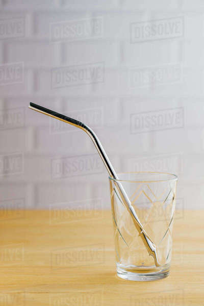 Shiny steel eco friendly sustainable straw in empty glass on wooden ...