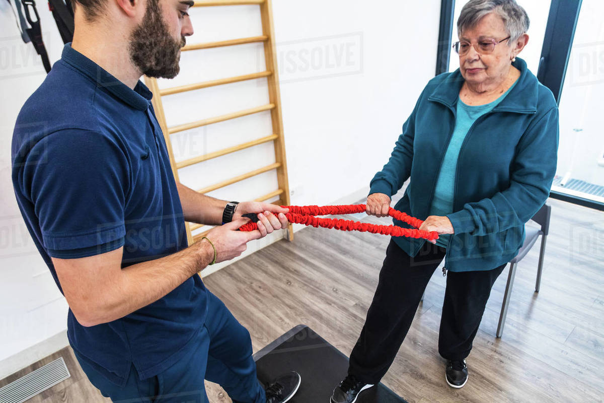 Fitness trainer and senior woman doing physiotherapy exercises with ...