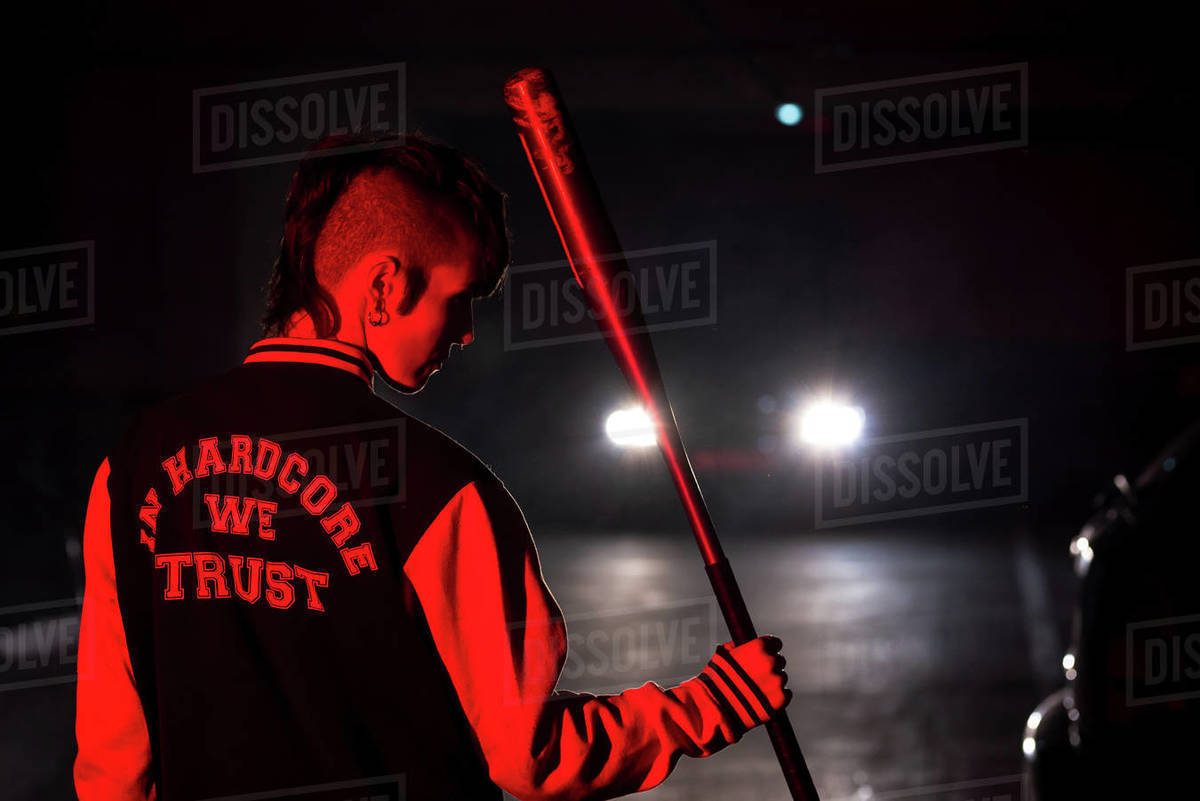 Back view of contemporary female in bomber jacket holding a black ...