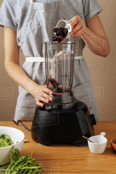 Unrecognizable female adding cooking ingredient into modern blender ...