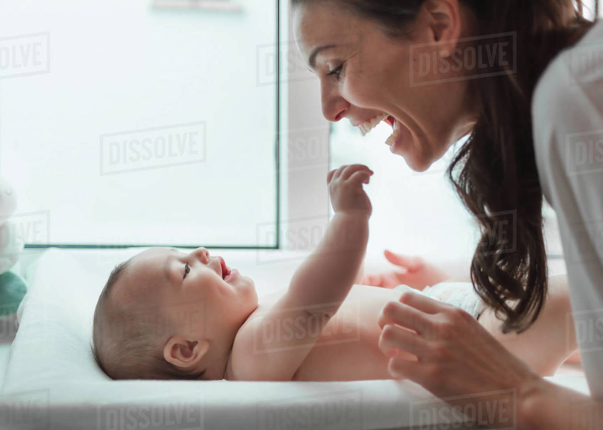 Side view of content mother laughing while leaning over lying on ...