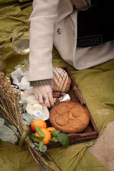From above anonymous woman in elegant coat grabbing food over tray with ...