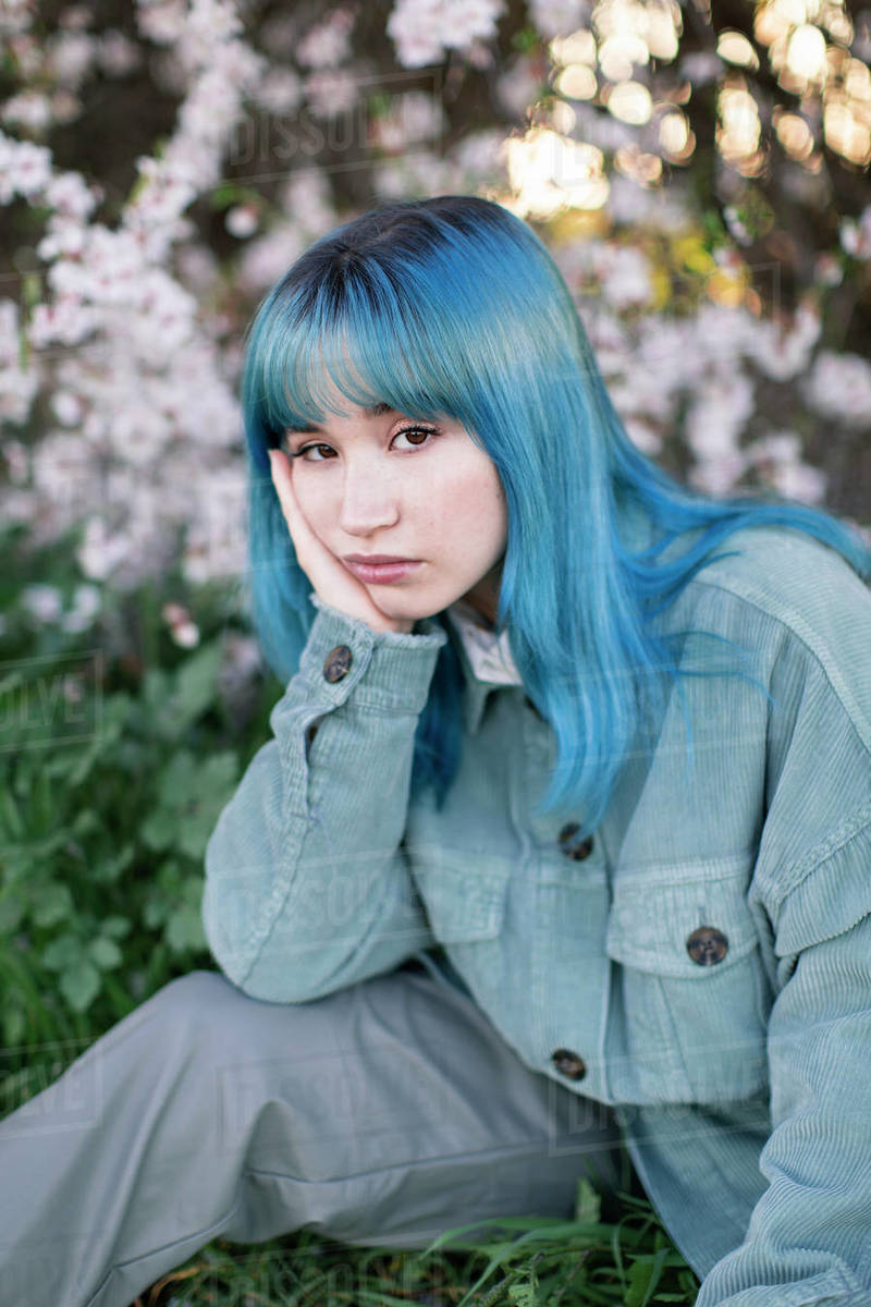 Sad millennial female model with blue hair in stylish outfit looking at ...