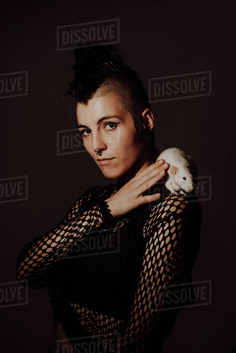 Confident woman with mohawk carrying white rat on shoulder and looking ...