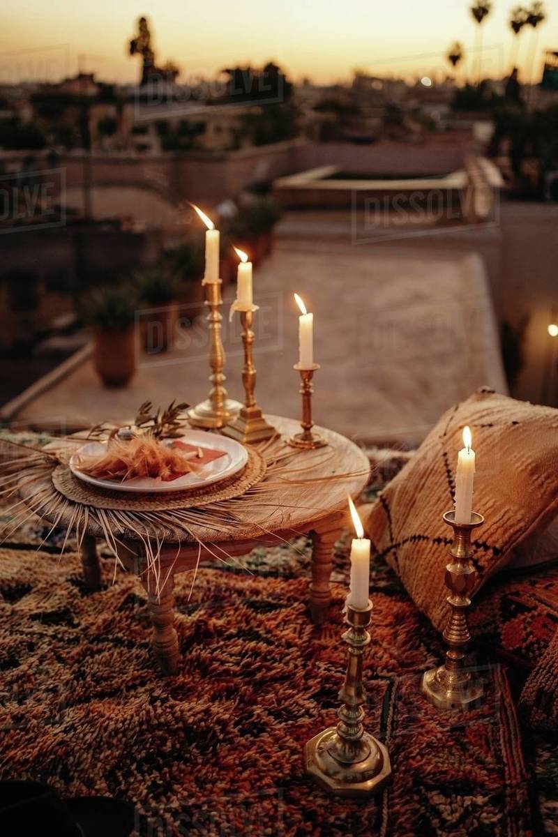 Composition in Arabic style with small round table with burning candles ...
