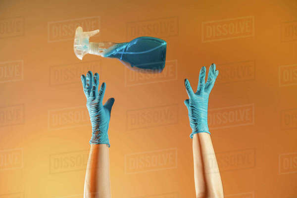 Unrecognizable medic in surgical gloves tossing plastic bottle of ...