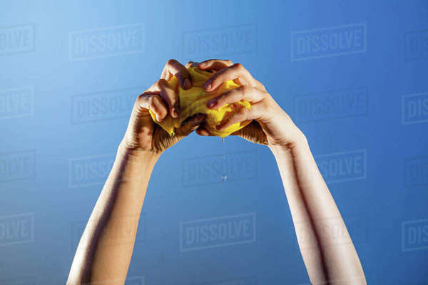 Faceless person wringing wet rag during house cleaning on blue ...