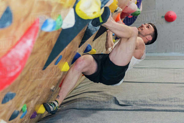 From bellow side view of strong male athlete in sportswear climbing on ...