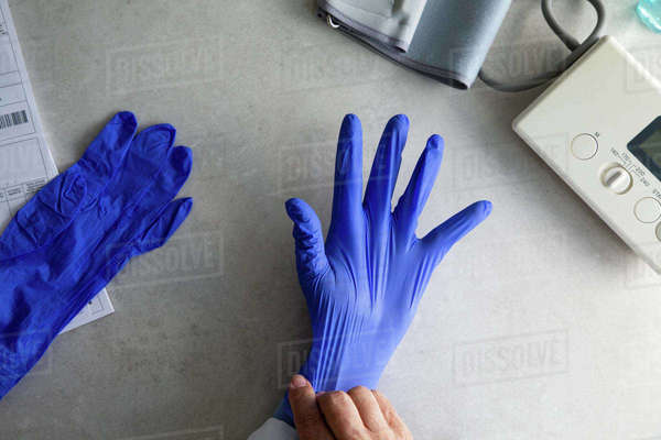 From above of crop male general practitioner putting on disposable ...