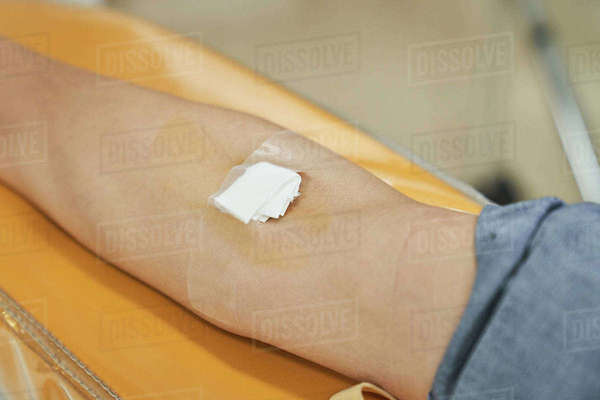 From above of crop anonymous female donor with patch on hand sitting in ...