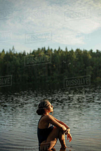 From above side view of slim female in swimsuit sitting with closed ...