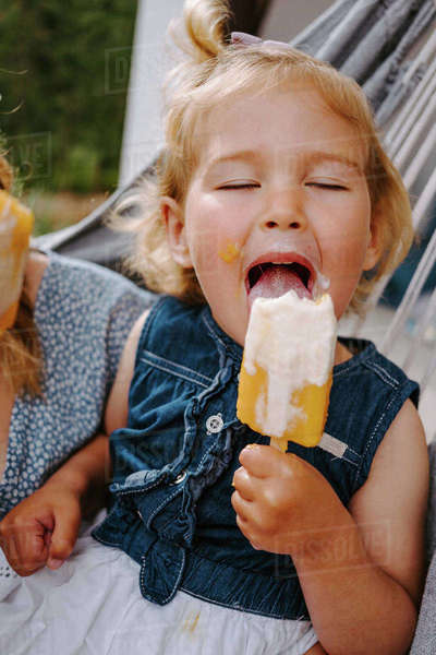 Content little kid eating homemade popsicle on stick while relaxing on ...