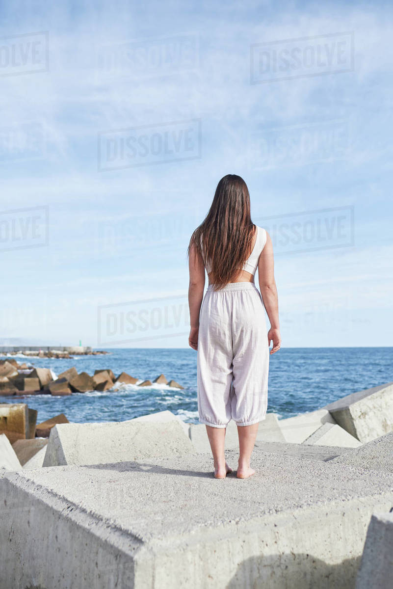 Back view full body of unrecognizable barefoot female in white clothes ...