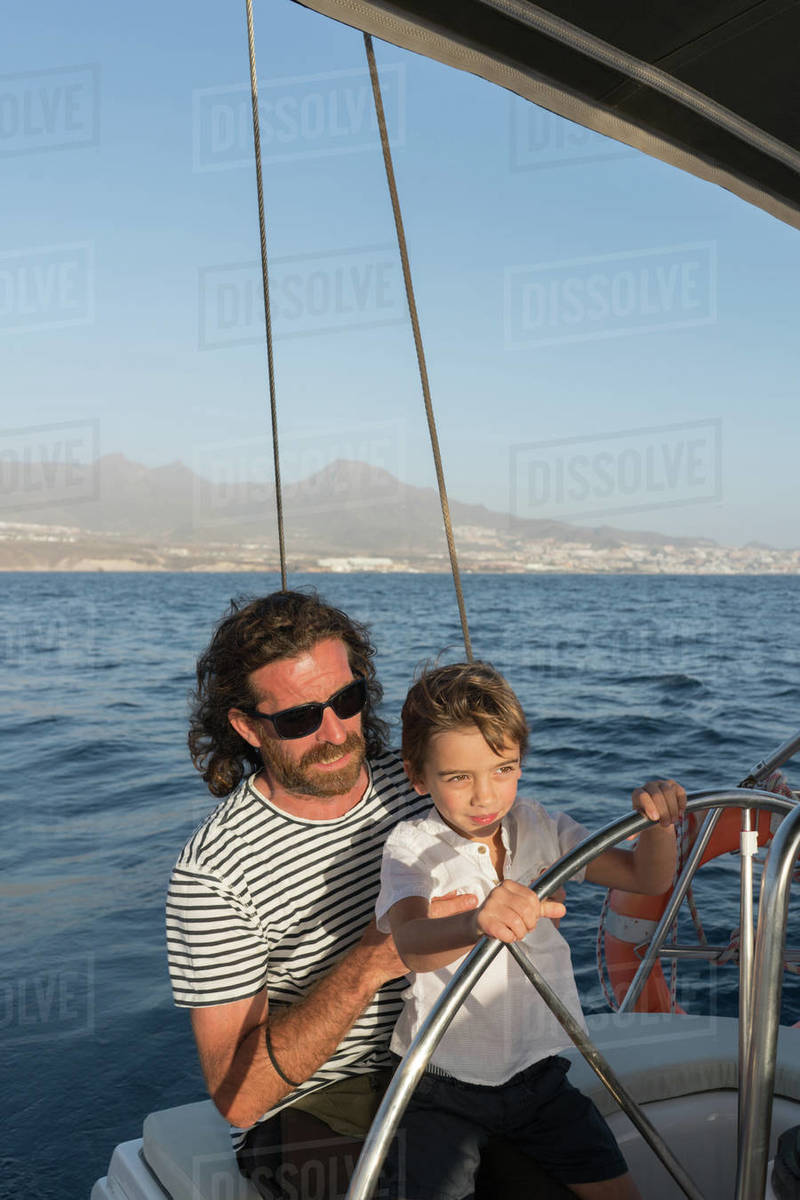 Happy father with children floating on expensive boat on sea and blue ...
