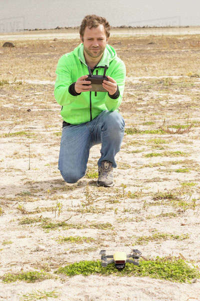 Immersed keen man lifting drone with camera from land using remote ...