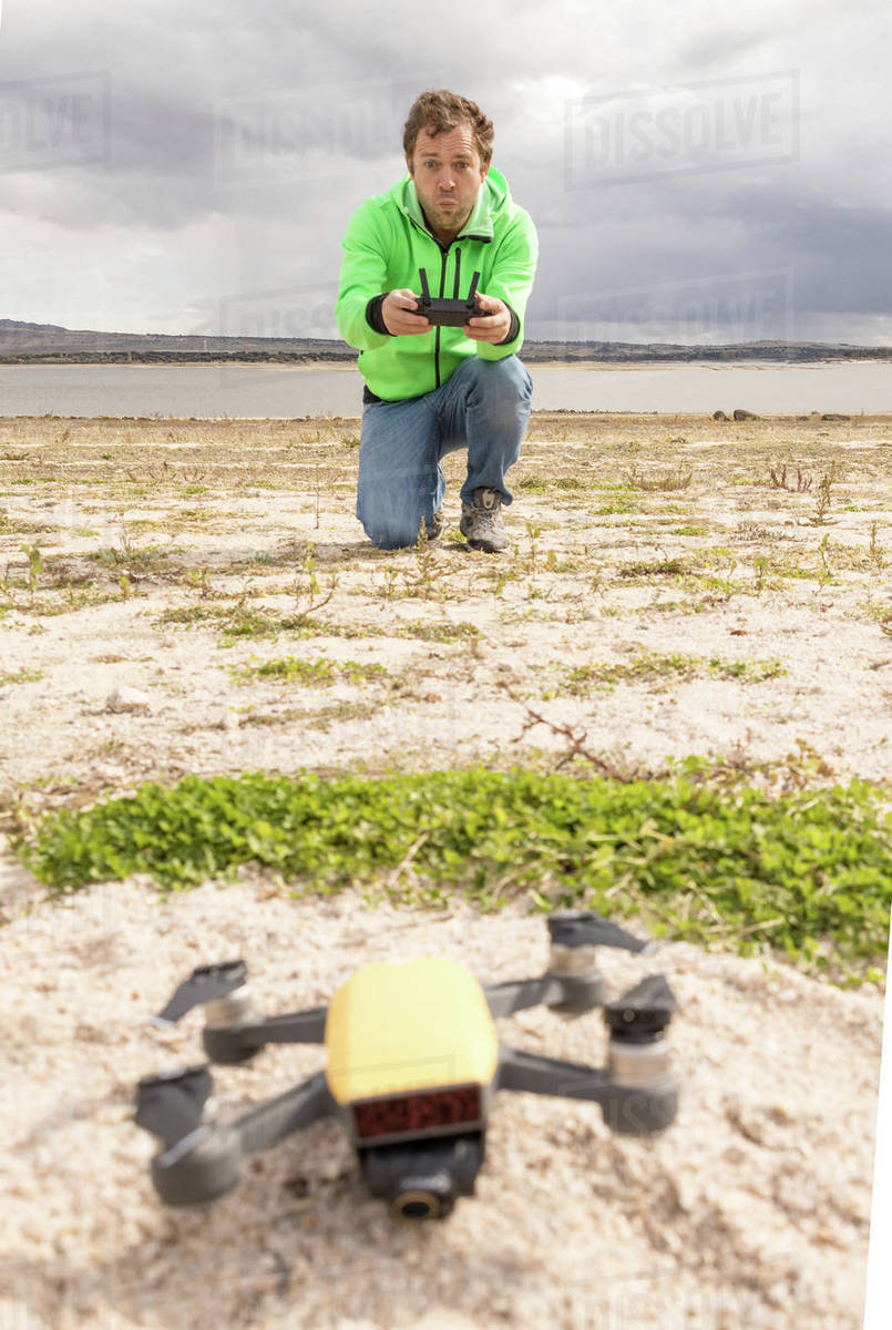 Immersed keen man lifting drone with camera from land using remote ...