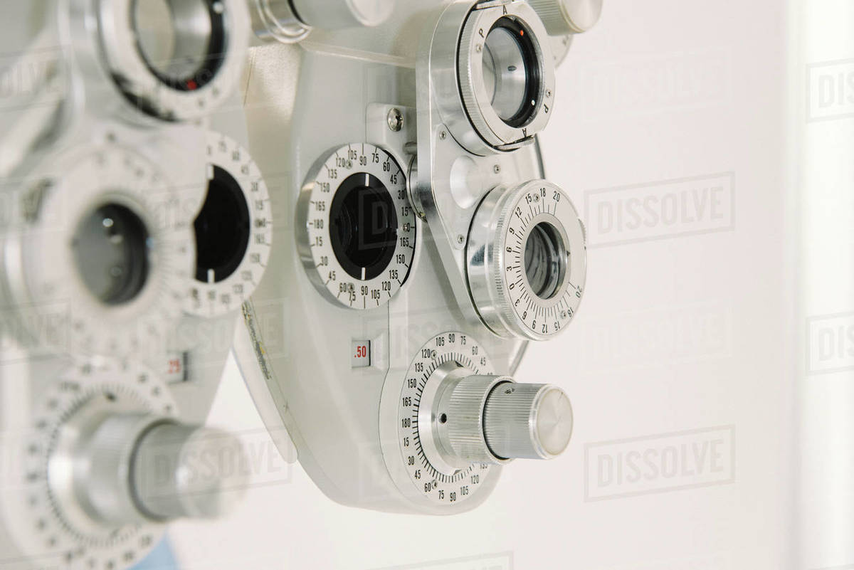 Modern vision test equipment and chair against white wall in optician ...