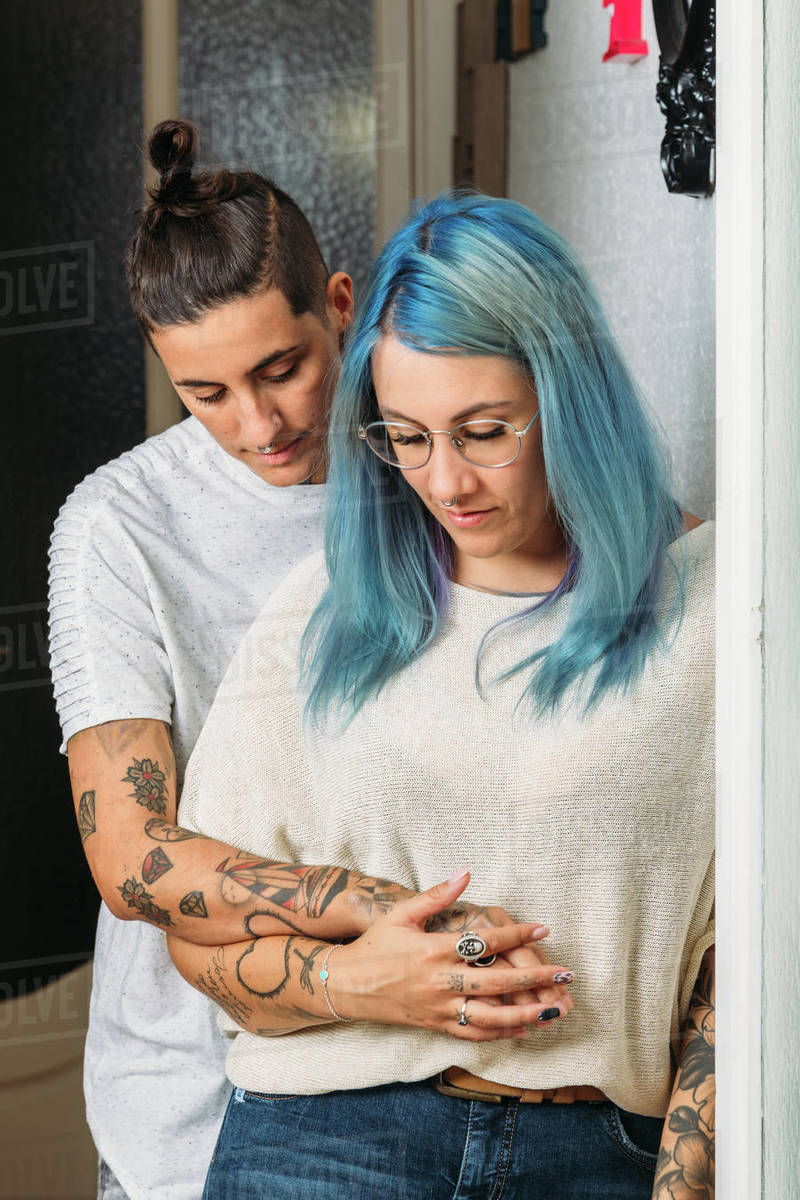 Androgynous tattooed woman embracing girlfriend with dyed hair from ...
