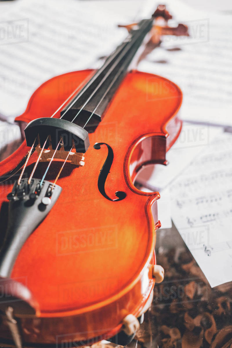 Top view of shiny violin arranged with white music sheets on table at ...