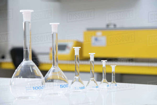 Various glass flasks placed in row on table and prepared for ...