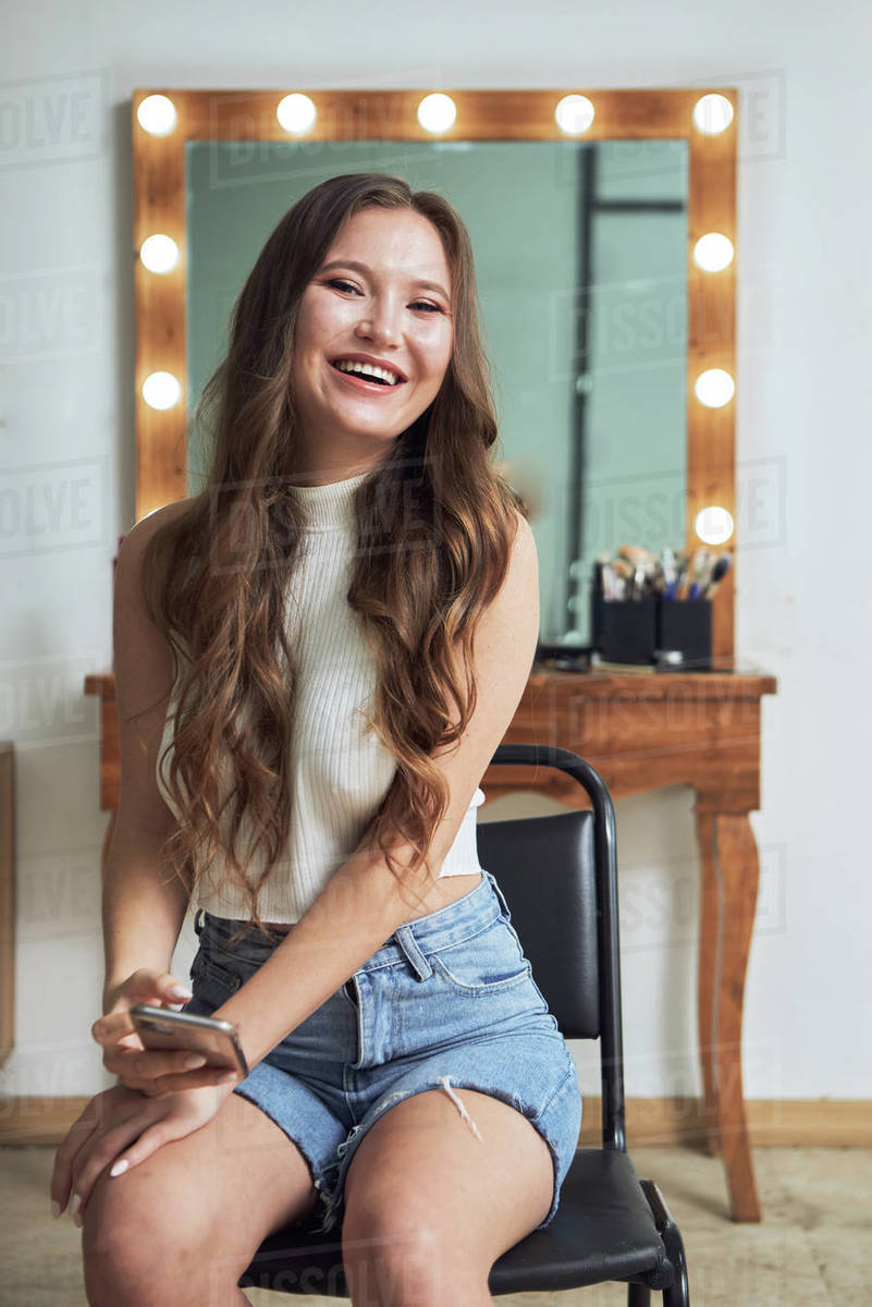 Positive stylish beautiful woman sitting gracefully on chair against ...