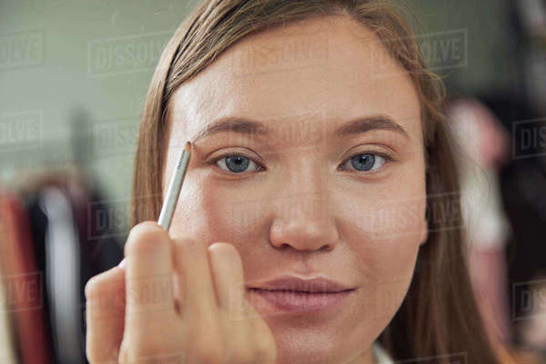 Crop focused makeup artist doing eyebrows on young beautiful female ...