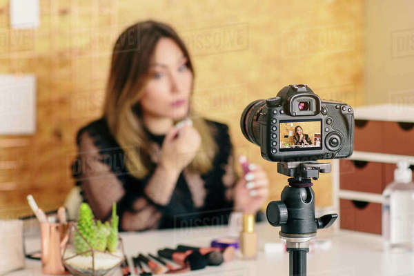 Charming female influencer in elegant wear applying lipstick while ...