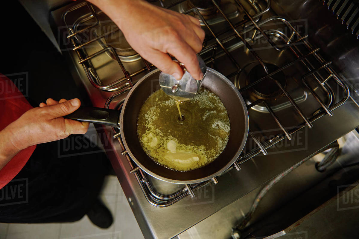 From above of crop anonymous chef pouring olive oil from metal can into ...